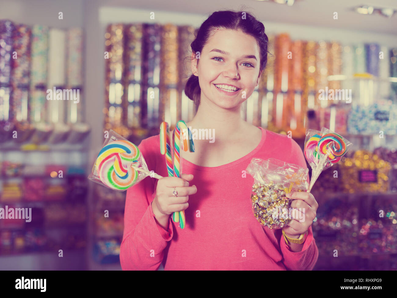 Happy brunette girl buying candies at shop Stock Photo - Alamy