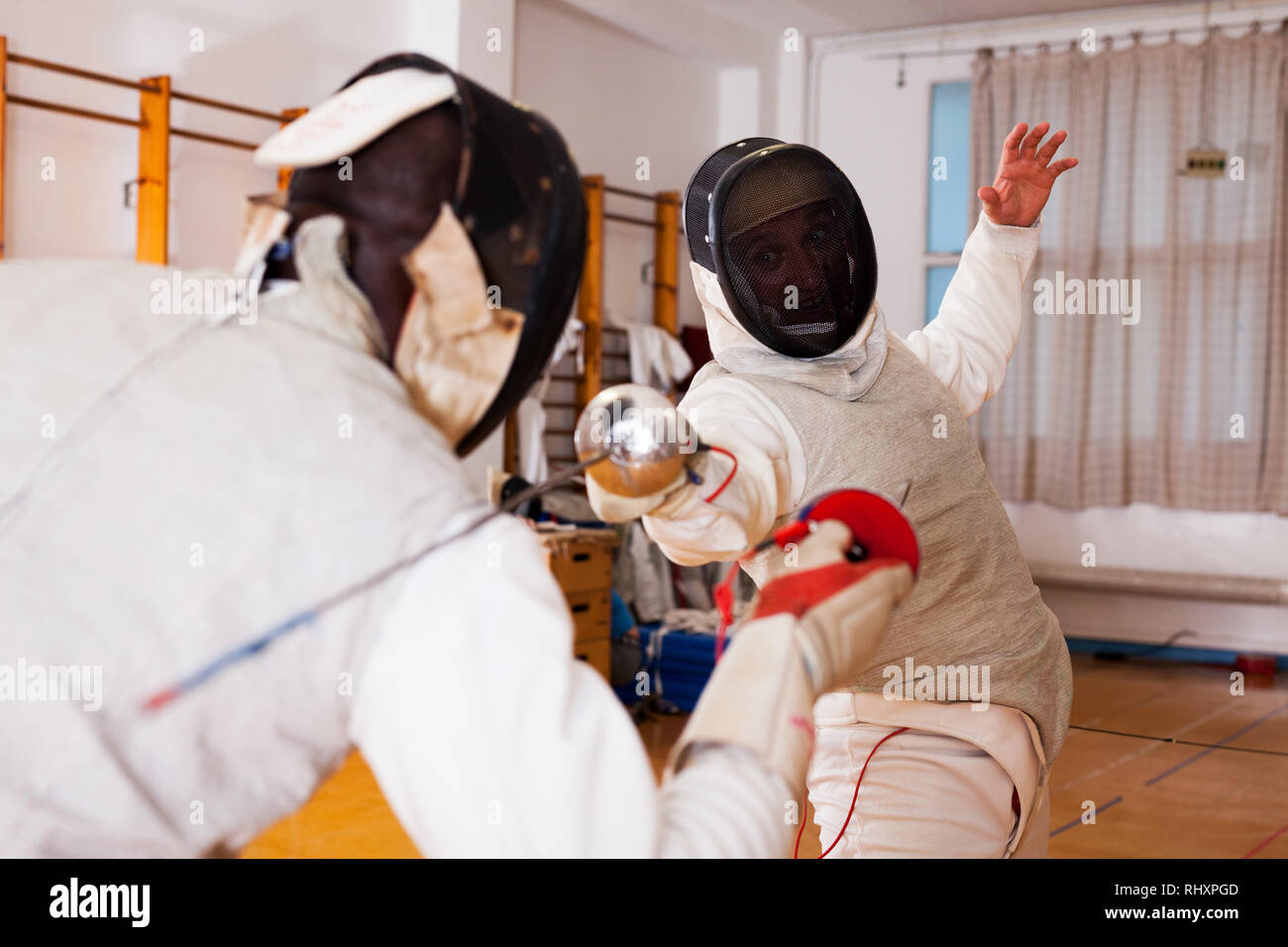 Portrait of active fencers at fencing workout, practicing attack ...
