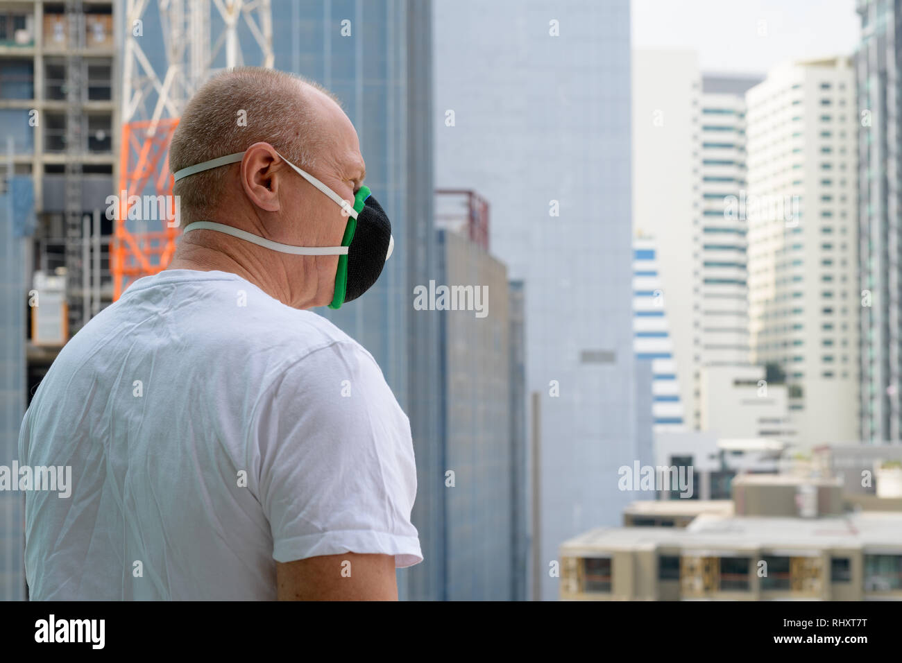 Senior man using face mask to protect from pollution smog in city Stock ...