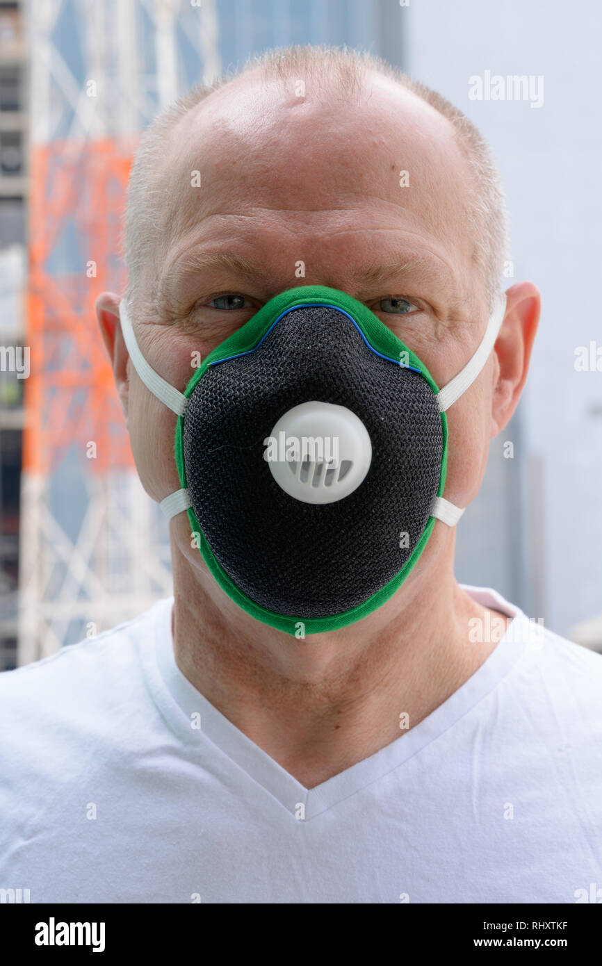 Senior man using face mask to protect from pollution smog in city Stock ...