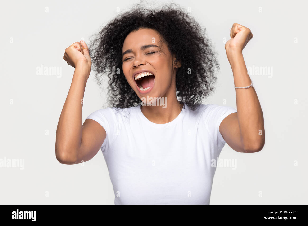 Overjoyed young african american woman screaming with joy celebrating ...