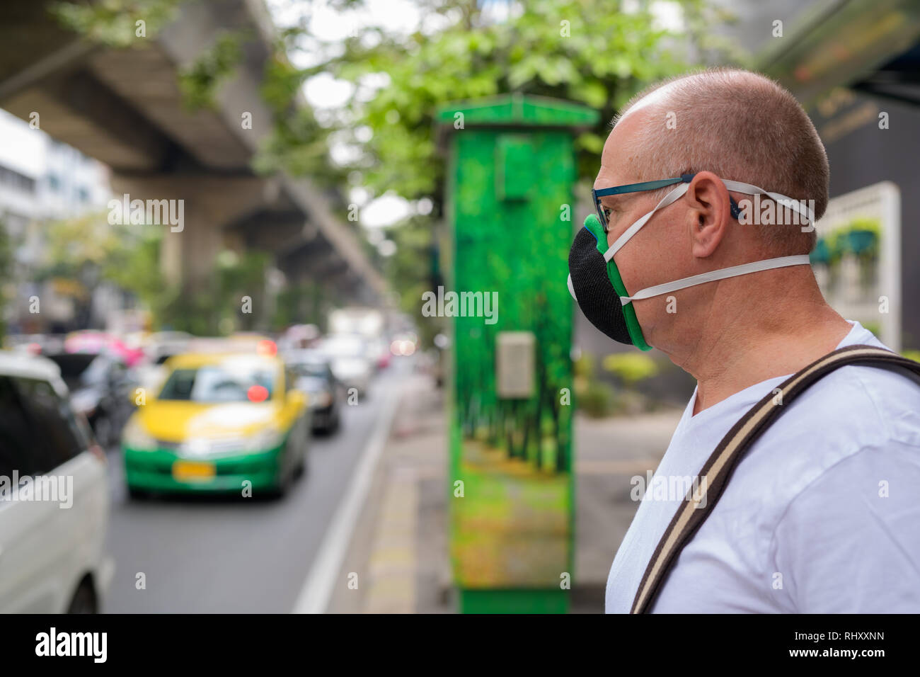 Senior man using face mask to protect from pollution smog in city Stock ...