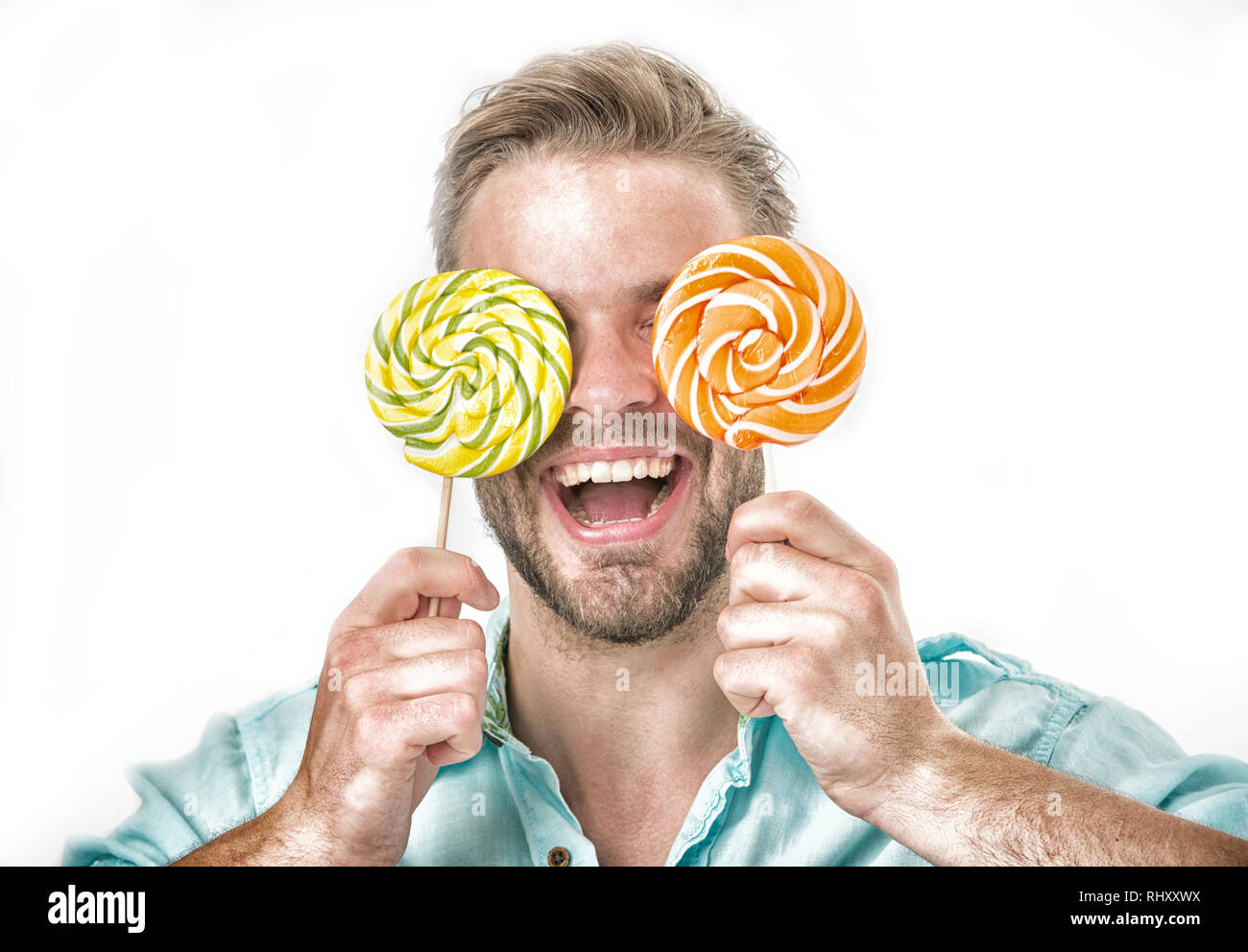 Man holds big lollipops on eyes as eyeglasses. Man with bristle likes ...