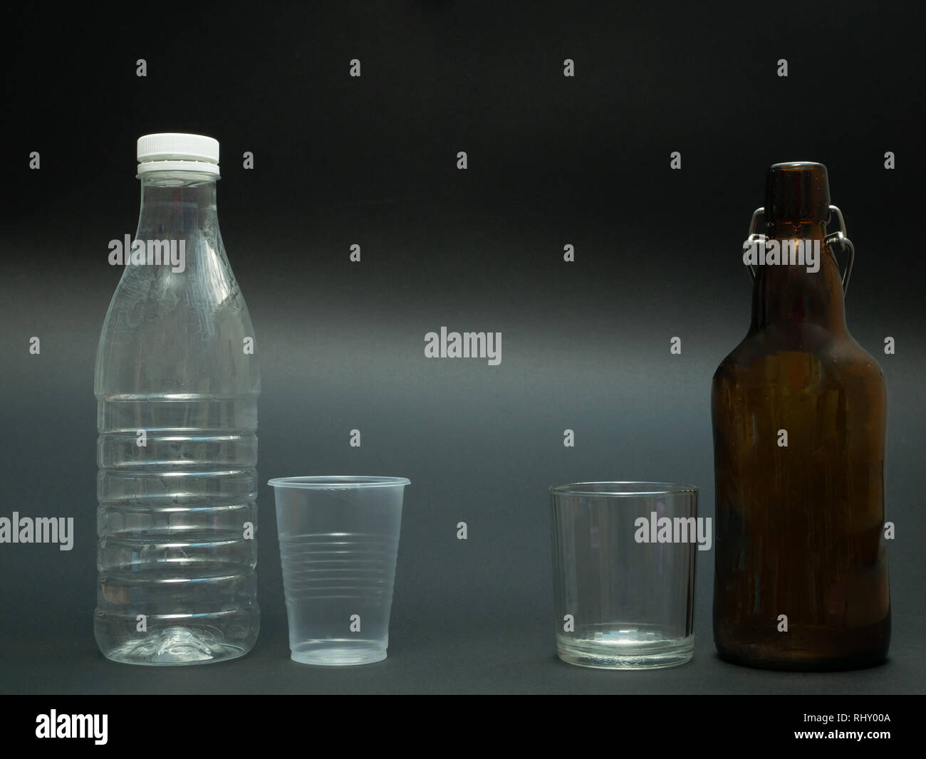 plastic vs glass materials bottle and cup on black dark background ...