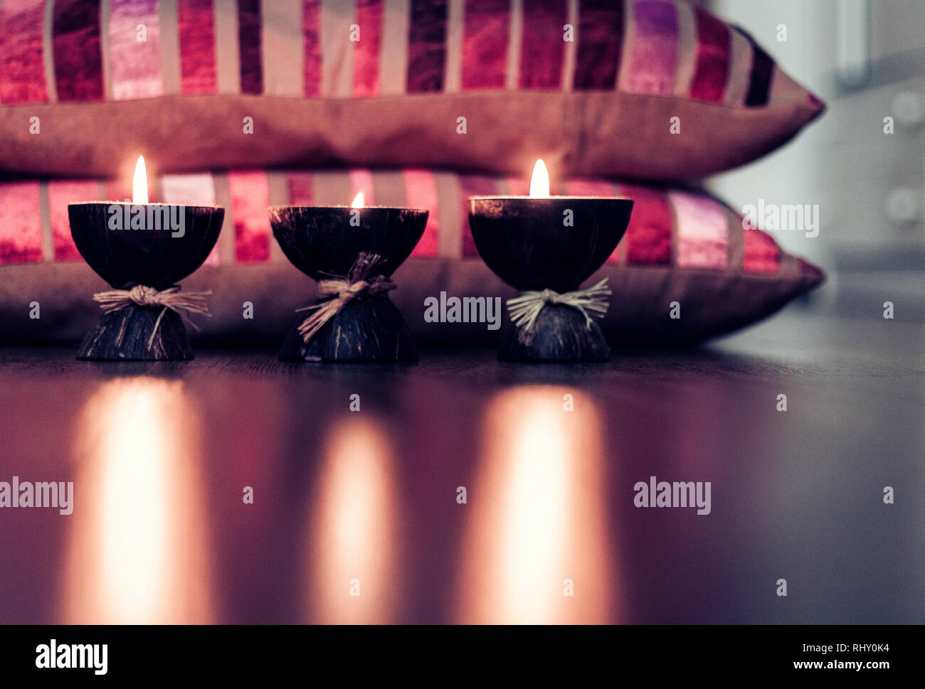 Burning spa aroma candles in coconut shell and burgundy pillows with ...