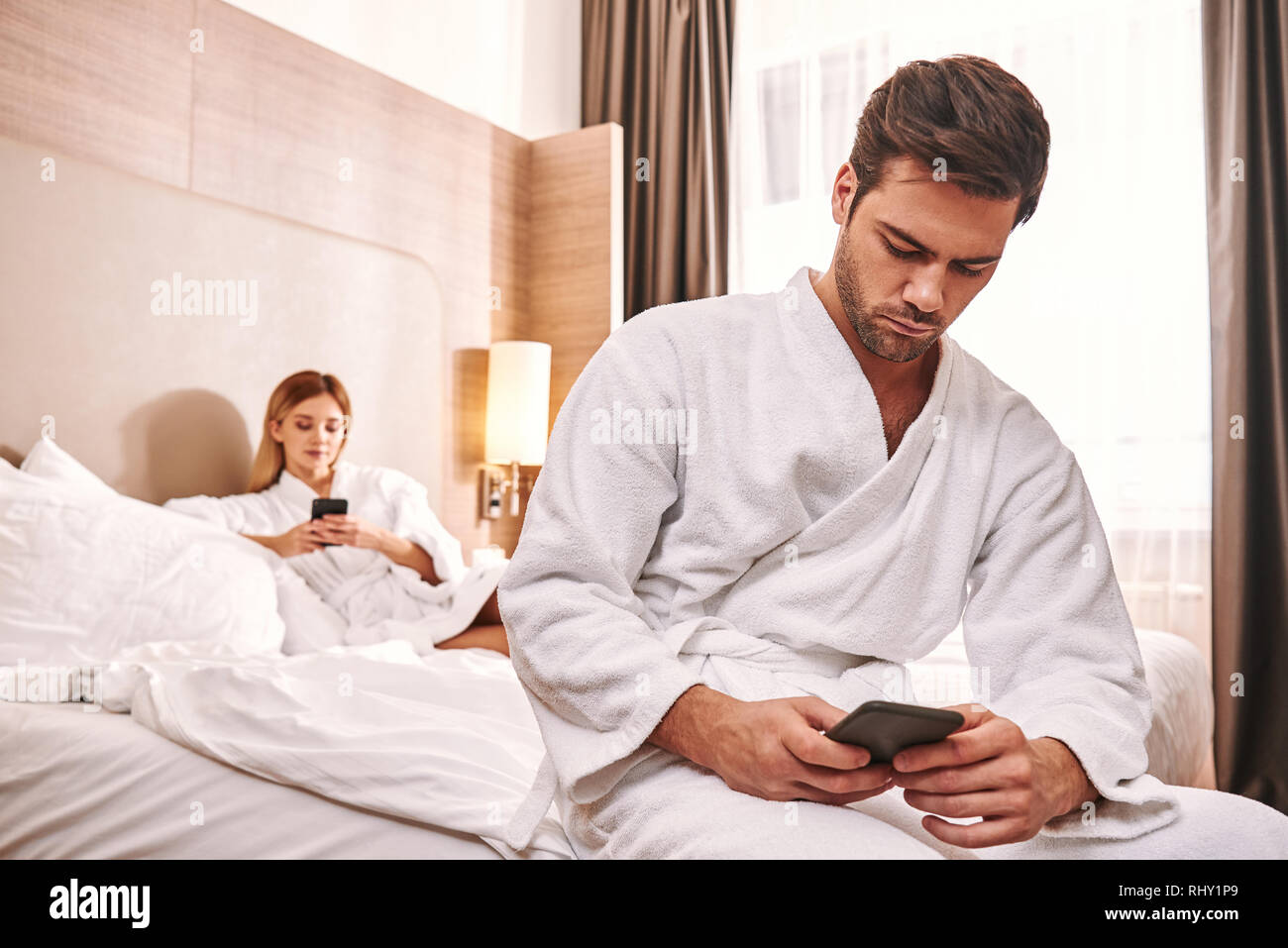 Life in smartphones. Couple are using smartphones in hotel room bed ...