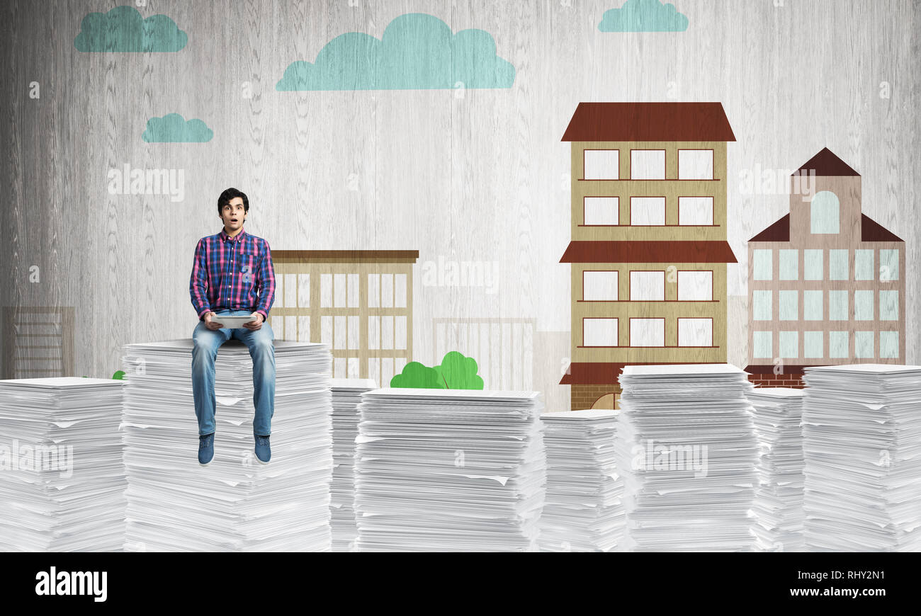 Young man sitting on pile of paper documents Stock Photo - Alamy