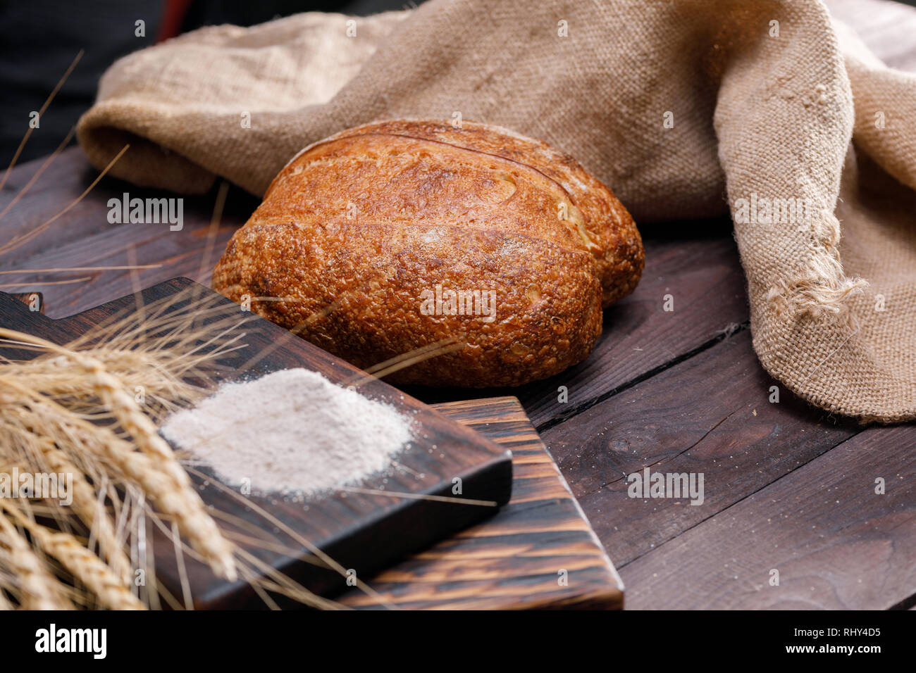 Crispy hand-made loaf of whole-grain rustic bread on a board covered ...