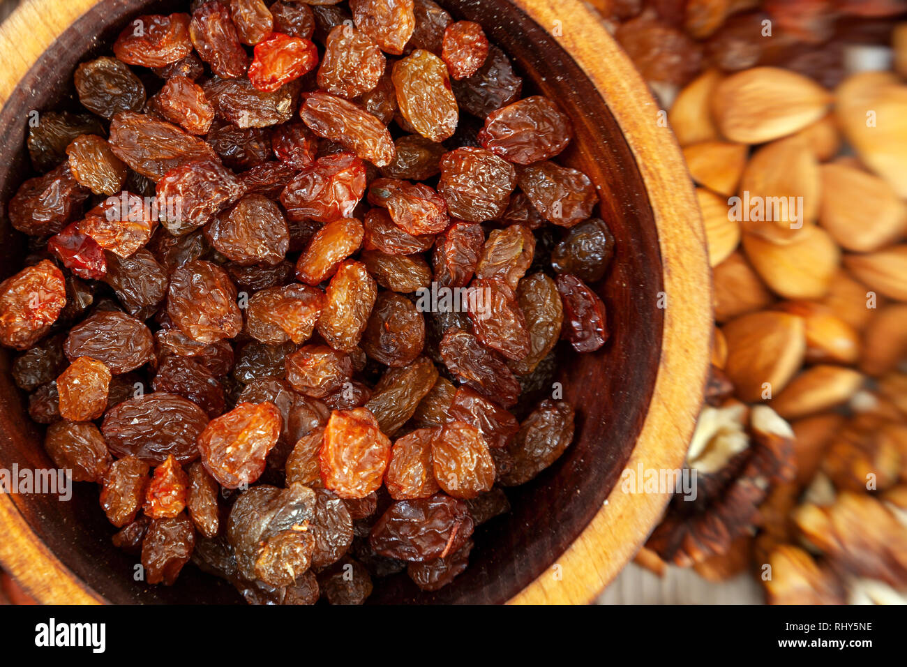Brown raisins in a wooden cedar plate on the background a scattering of ...