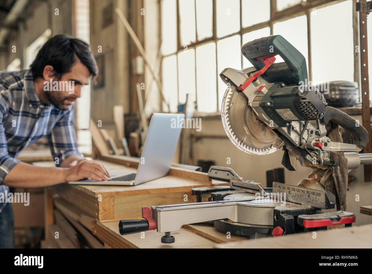 Carpenter leaning on a workbench full of tools working online Stock ...