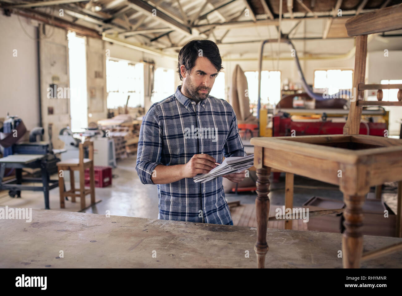Woodworker creating a new chair design in his furniture workshop Stock ...