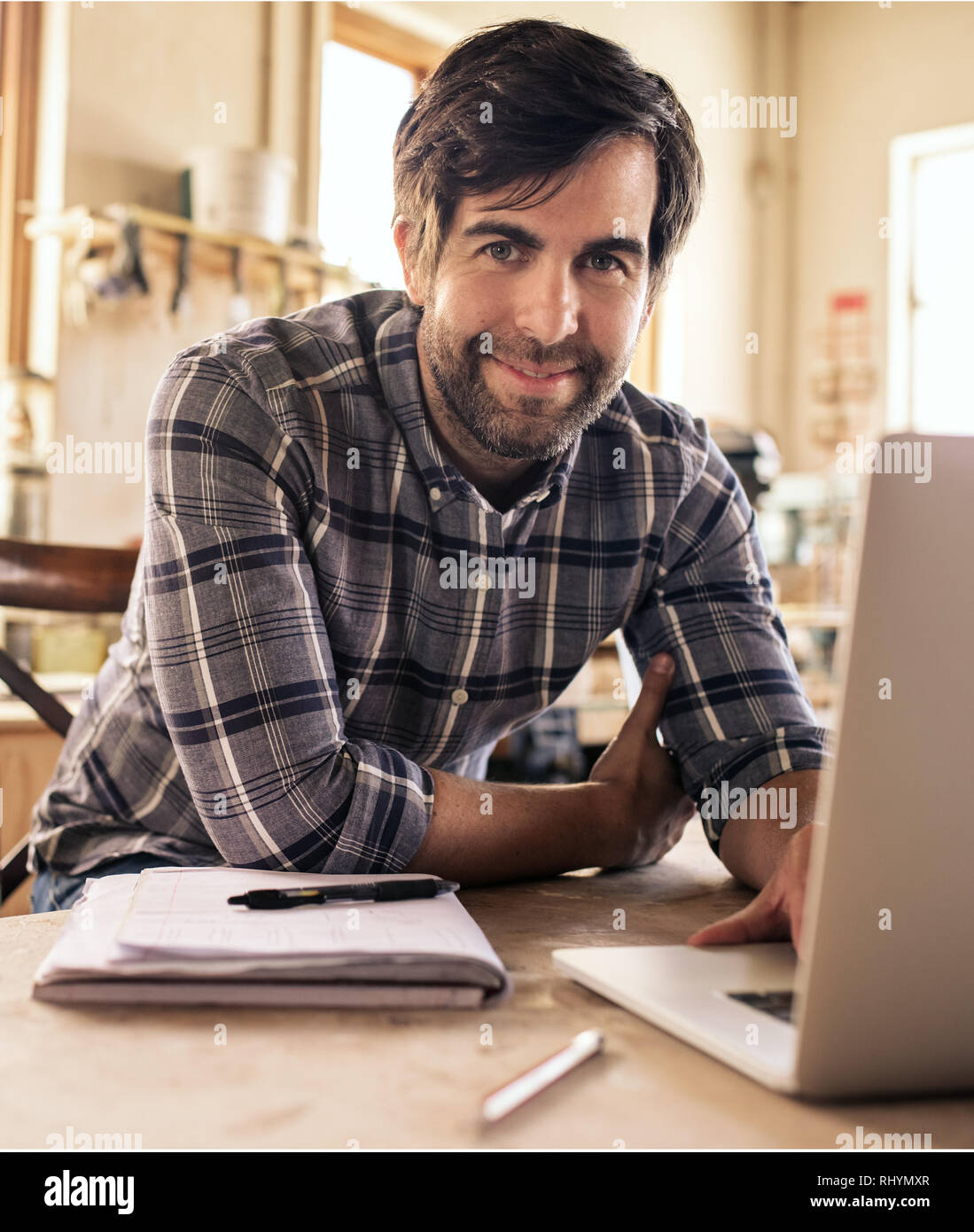 Young entrepreneur using a laptop in his workshop Stock Photo - Alamy