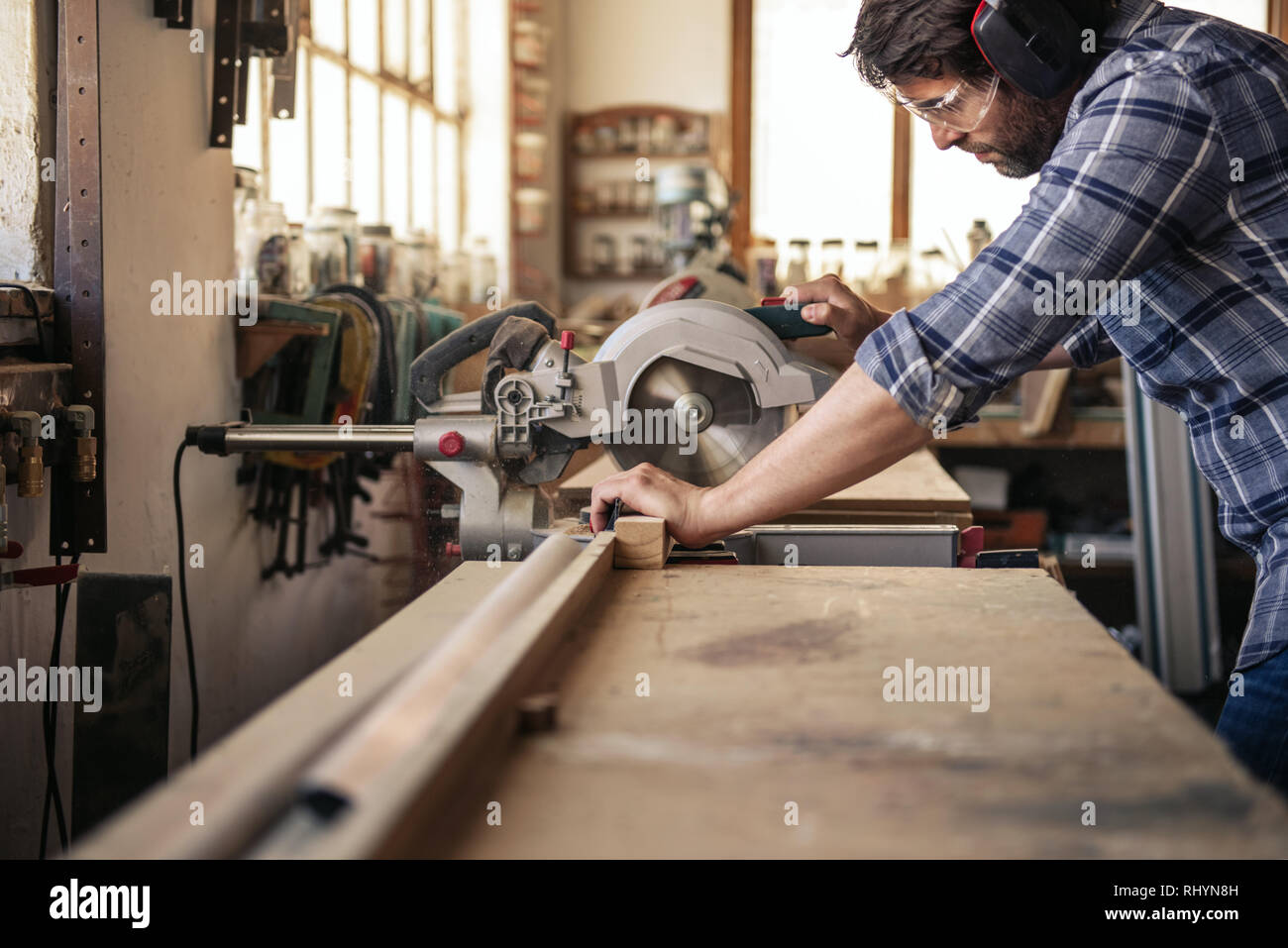 Woodworker cutting wood with a mitre saw in his workshop Stock Photo ...
