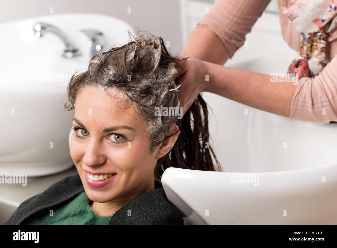 Attractive woman having her hair washed at a basin in a professional ...