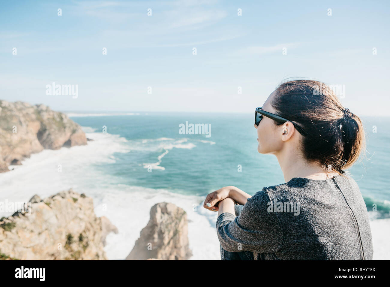The girl at the top of the cliff in solitude admires the beautiful view ...