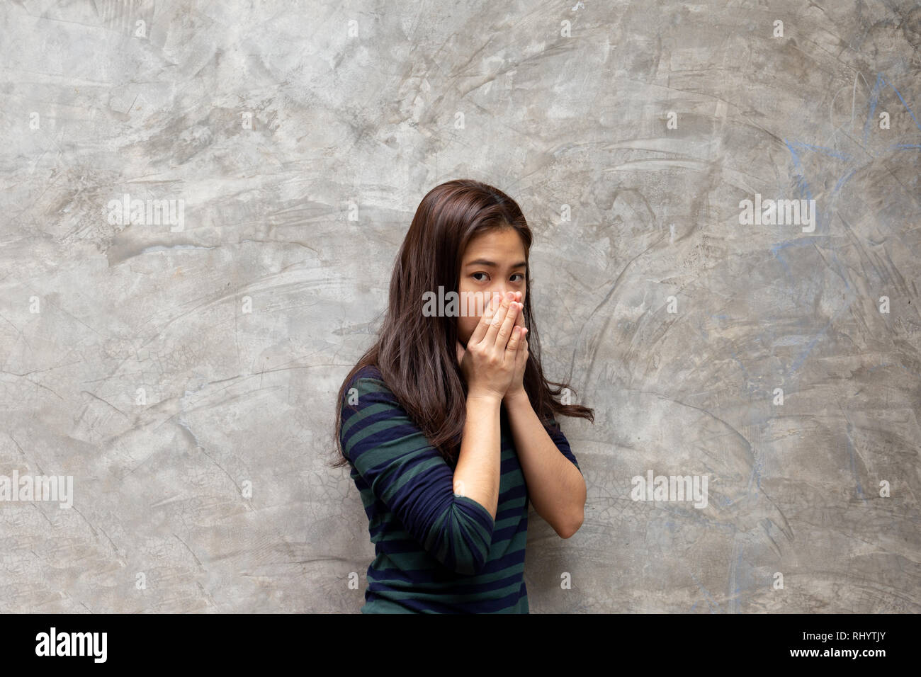 Young beautiful girl covers her nose with hands over gray background ... Young beautiful girl covers her nose with hands over gray background ...