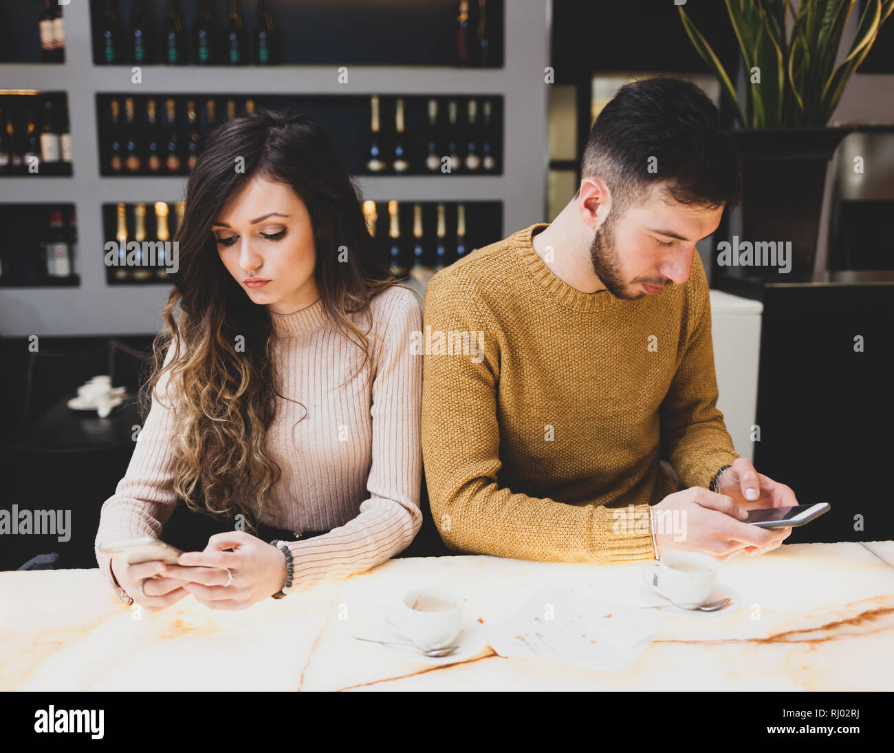 Young couple at the bar while using mobile phone. Social networks in ...