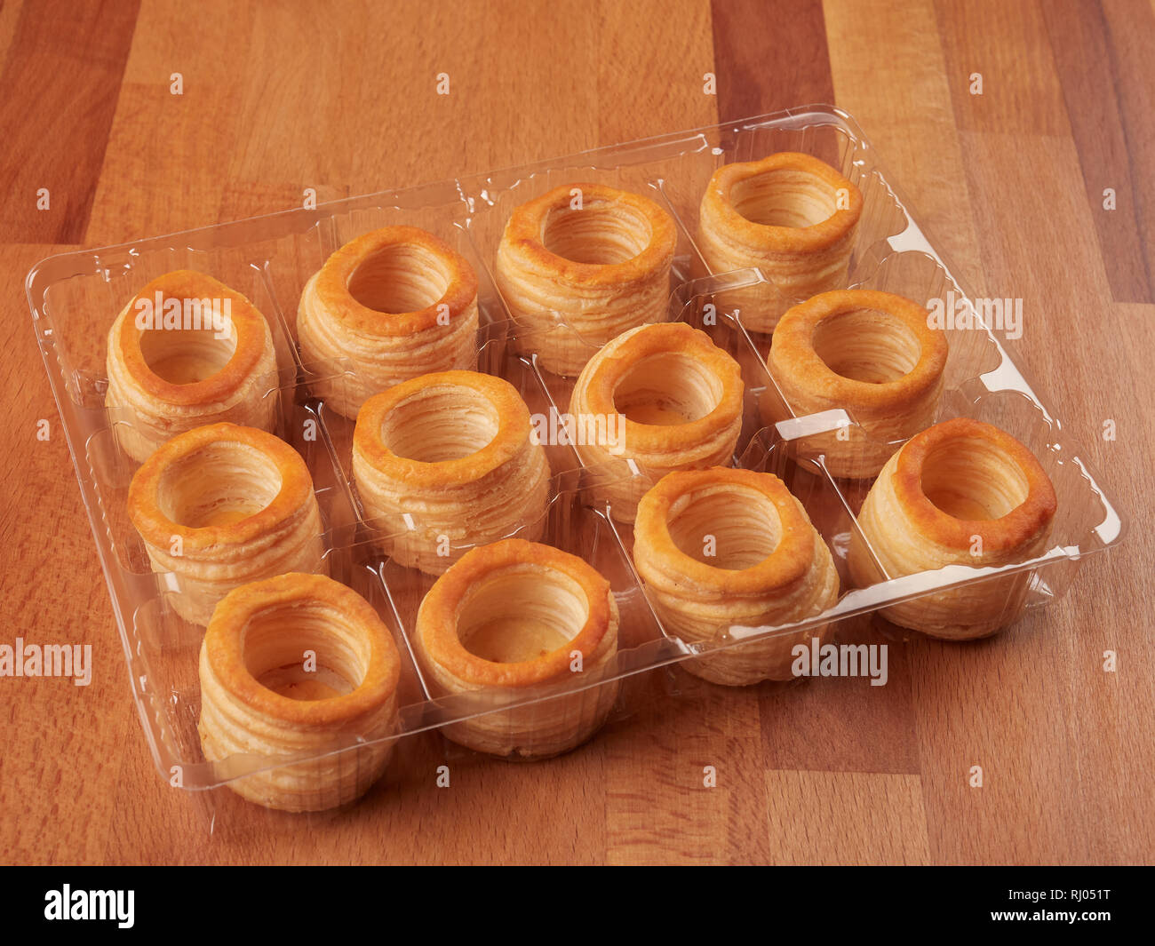 A tray of ready-made small puff pastry shells, on a wooden board Stock ...