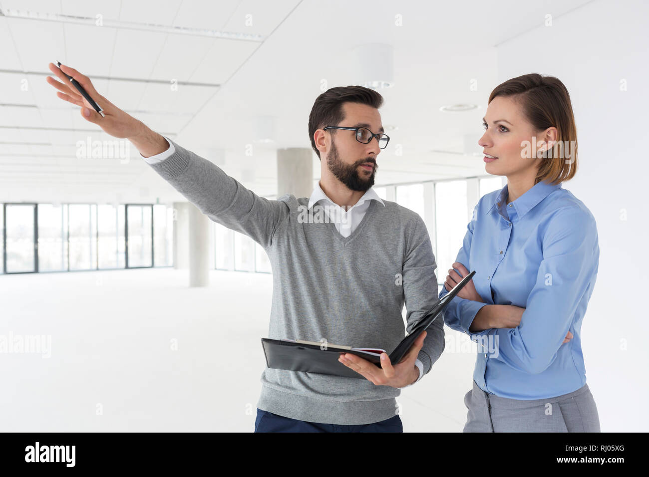 Businessman with file explaining colleague at new office Stock Photo ...