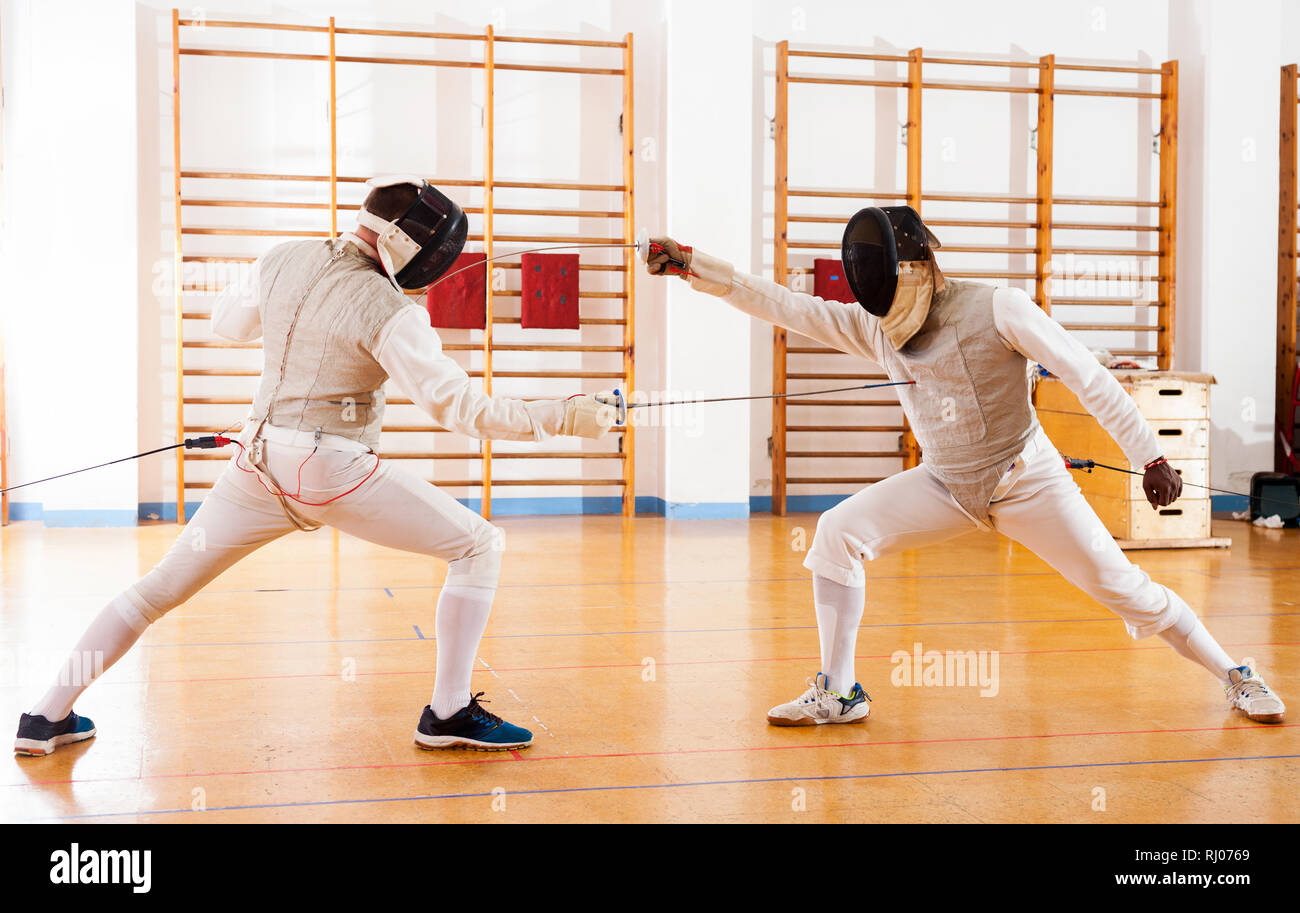 active young fencers at fencing workout, practicing attack movements in ...