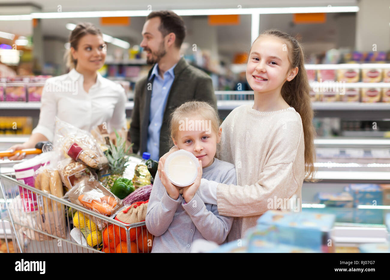 Smiling kids with parents are standing with purchases in the ...
