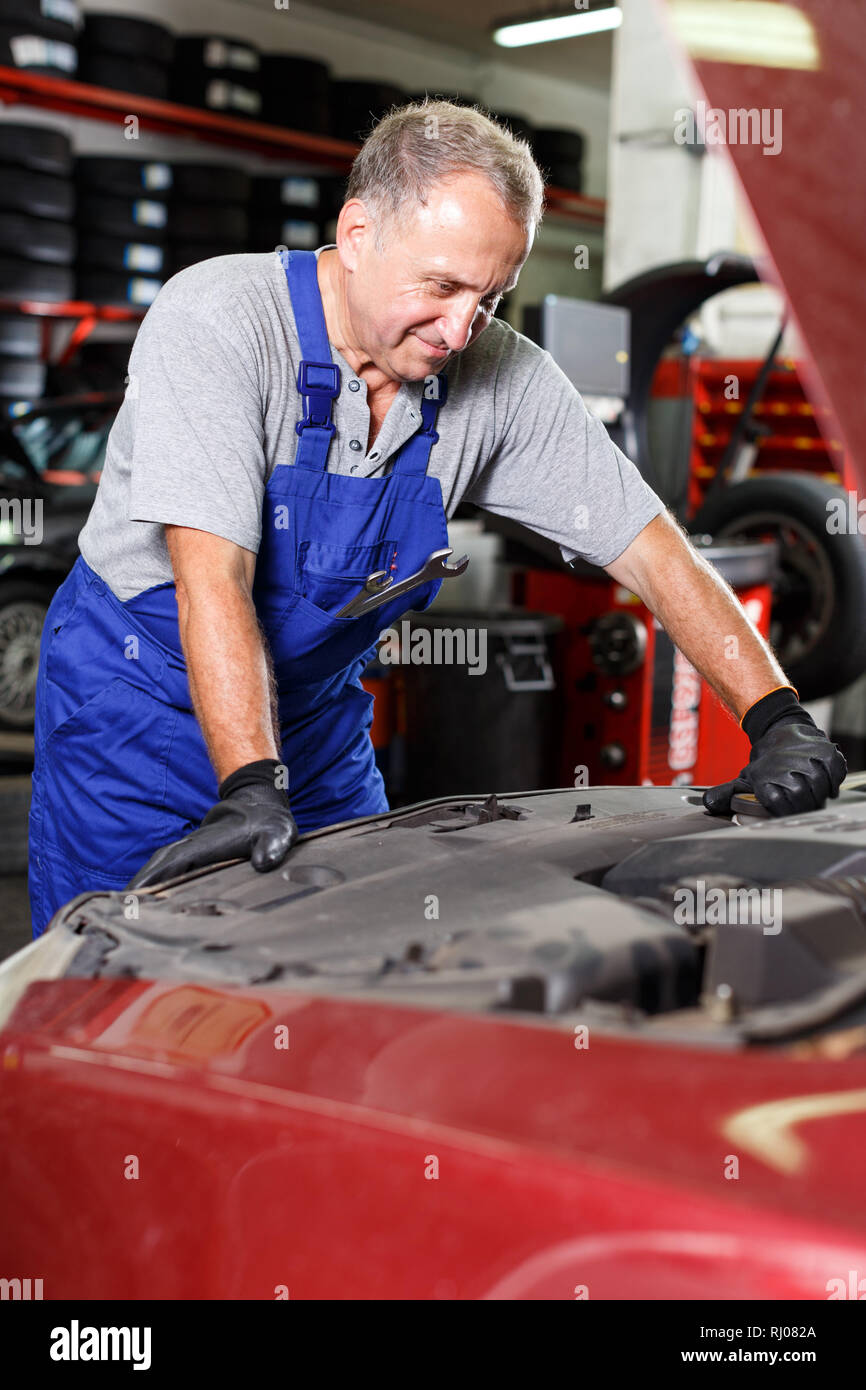 Portrait of thoughtful professional mature man car mechanician standing ...