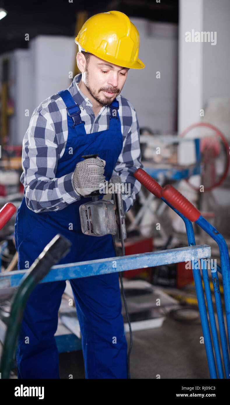 Young smiling guy using angle grinder for construction work at ...