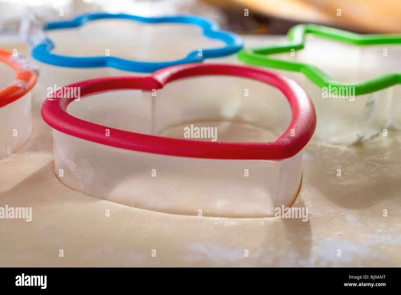Group of 4 cookie cutters on a sheet of sugar cookie dough: heart, star ...