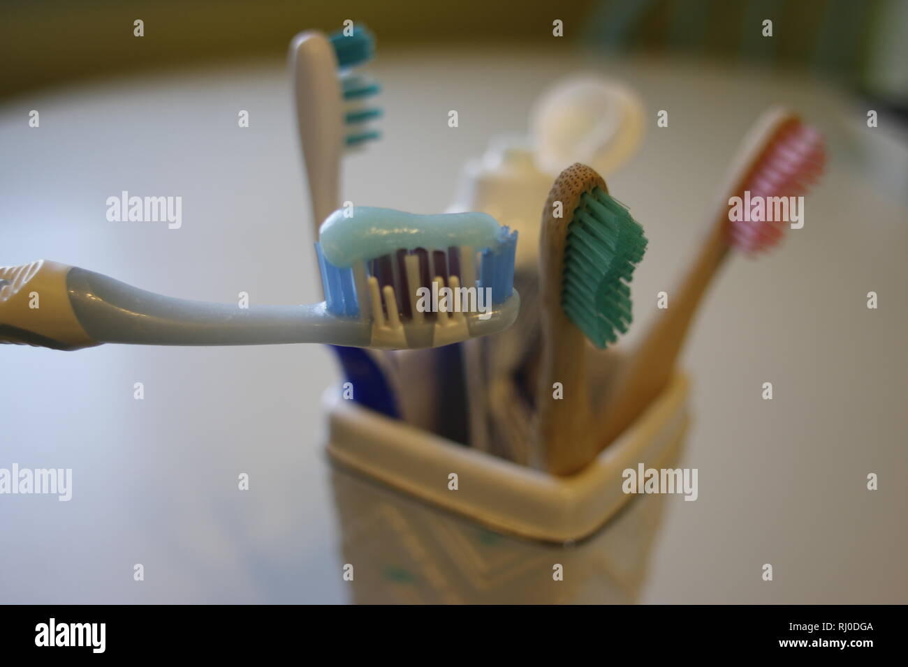 Cup with toothbrushes and paste on white background Stock Photo - Alamy