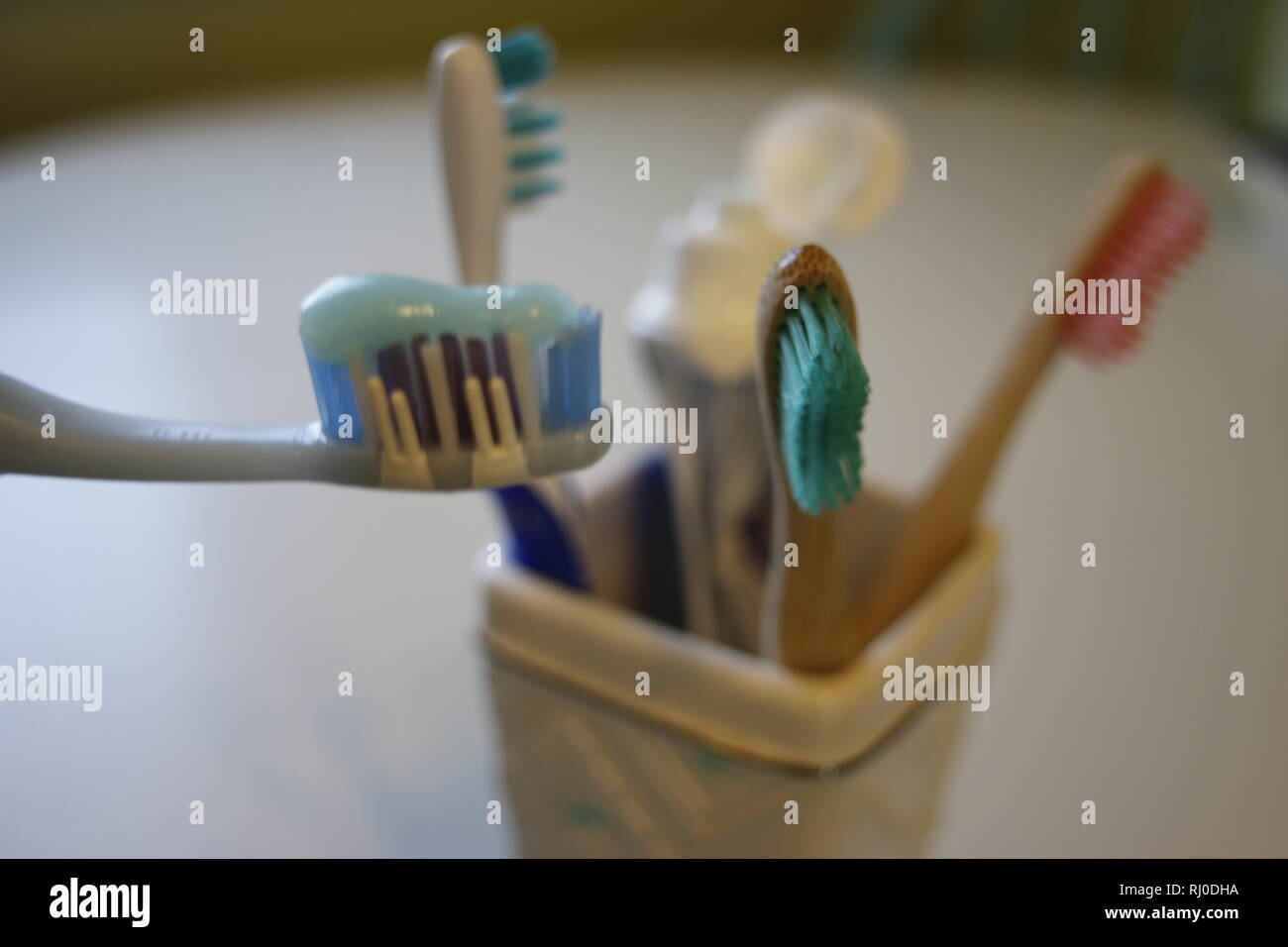 Cup with toothbrushes and paste on white background Stock Photo - Alamy
