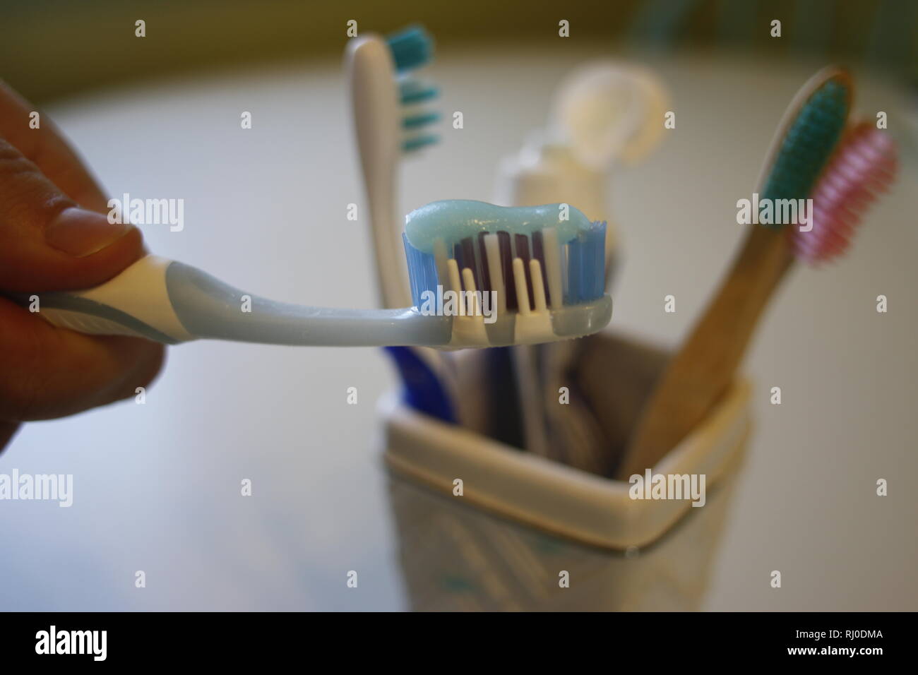 Cup with toothbrushes and paste on white background Stock Photo - Alamy