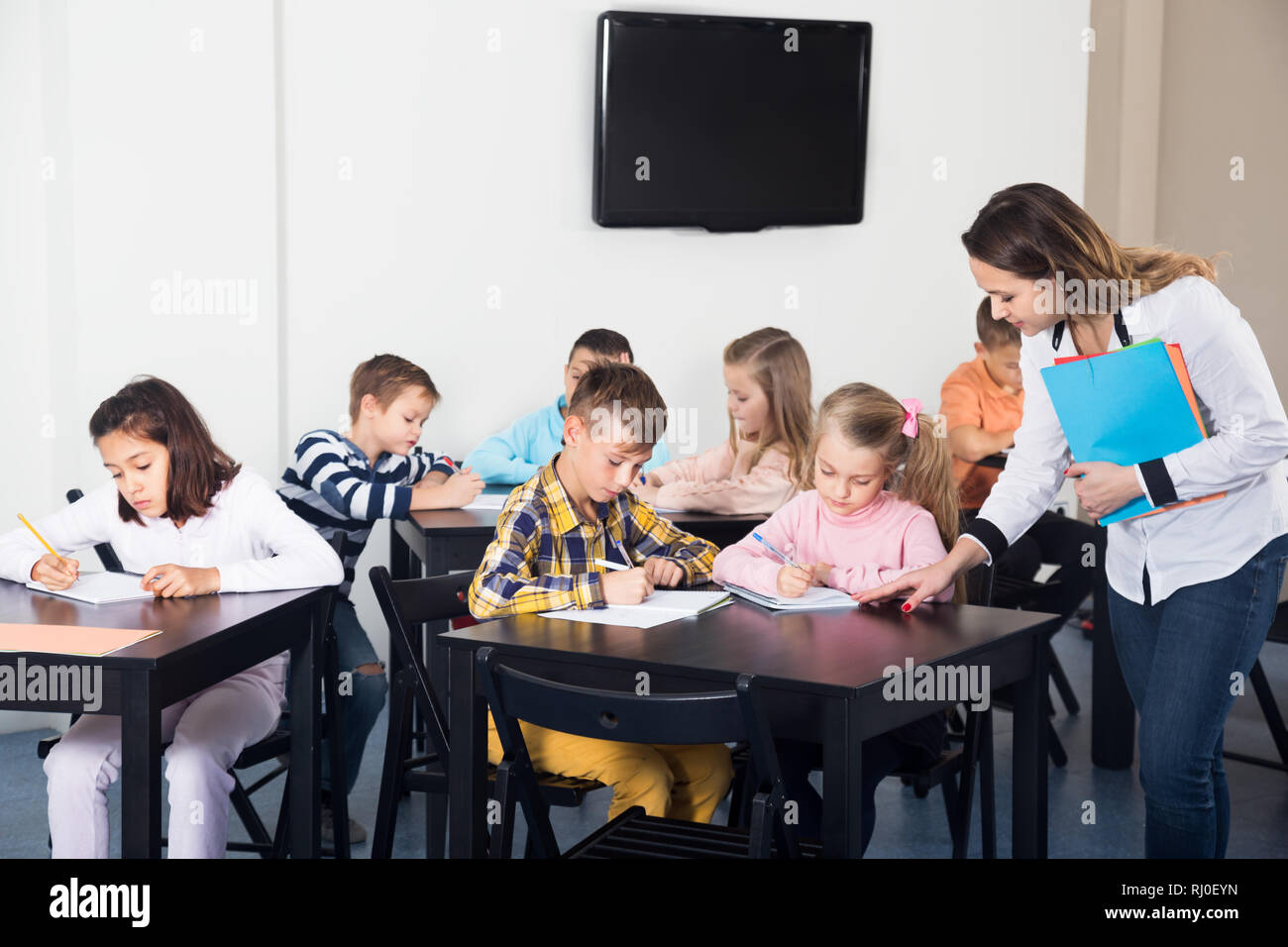Professor and elementary age children at a classroom in school Stock ...