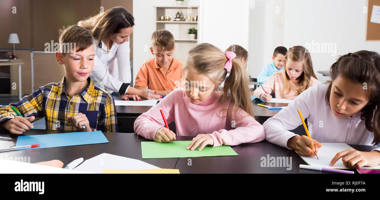 Elementary age children drawing at classroom in school Stock Photo - Alamy
