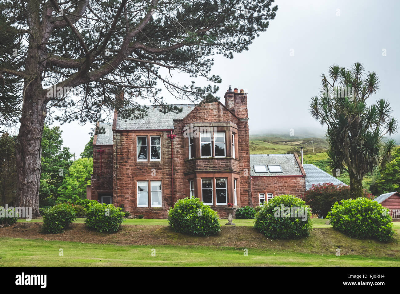 Traditional Irish stone cottage behind the green lawn. Northern Ireland ...