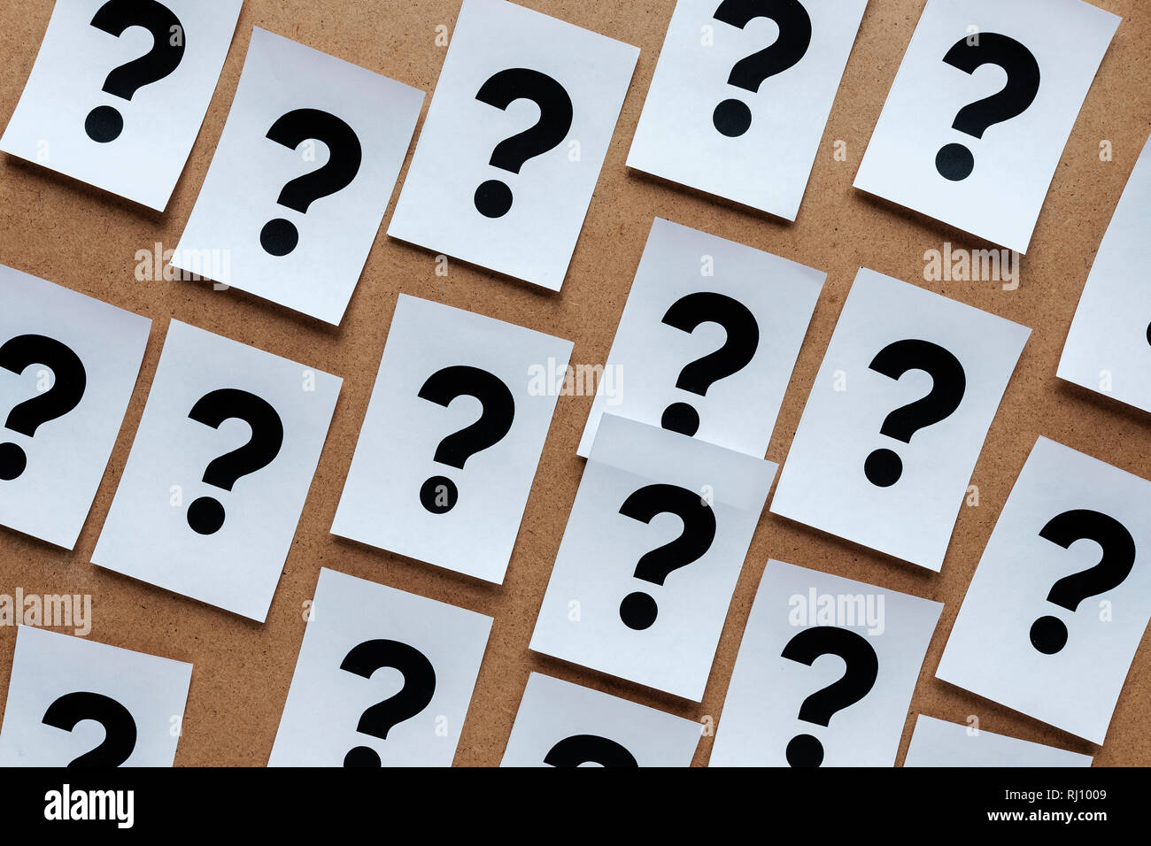 Bold black question marks on paper cards scattered randomly over a ...