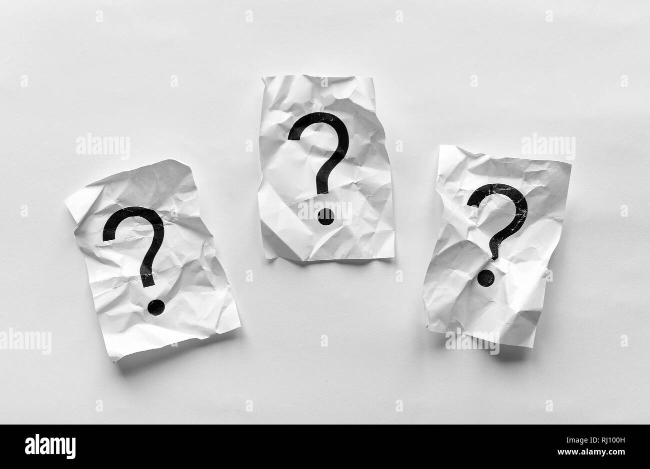Three crumpled pages of paper with question marks on a white background ...