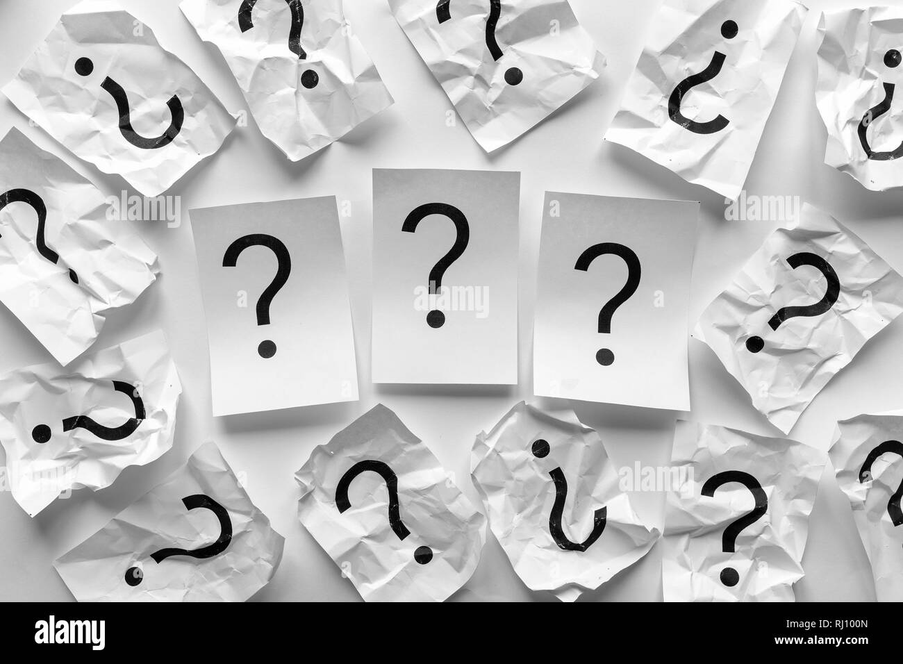 Three question marks on white cards surrounded by a frame of crumpled ...