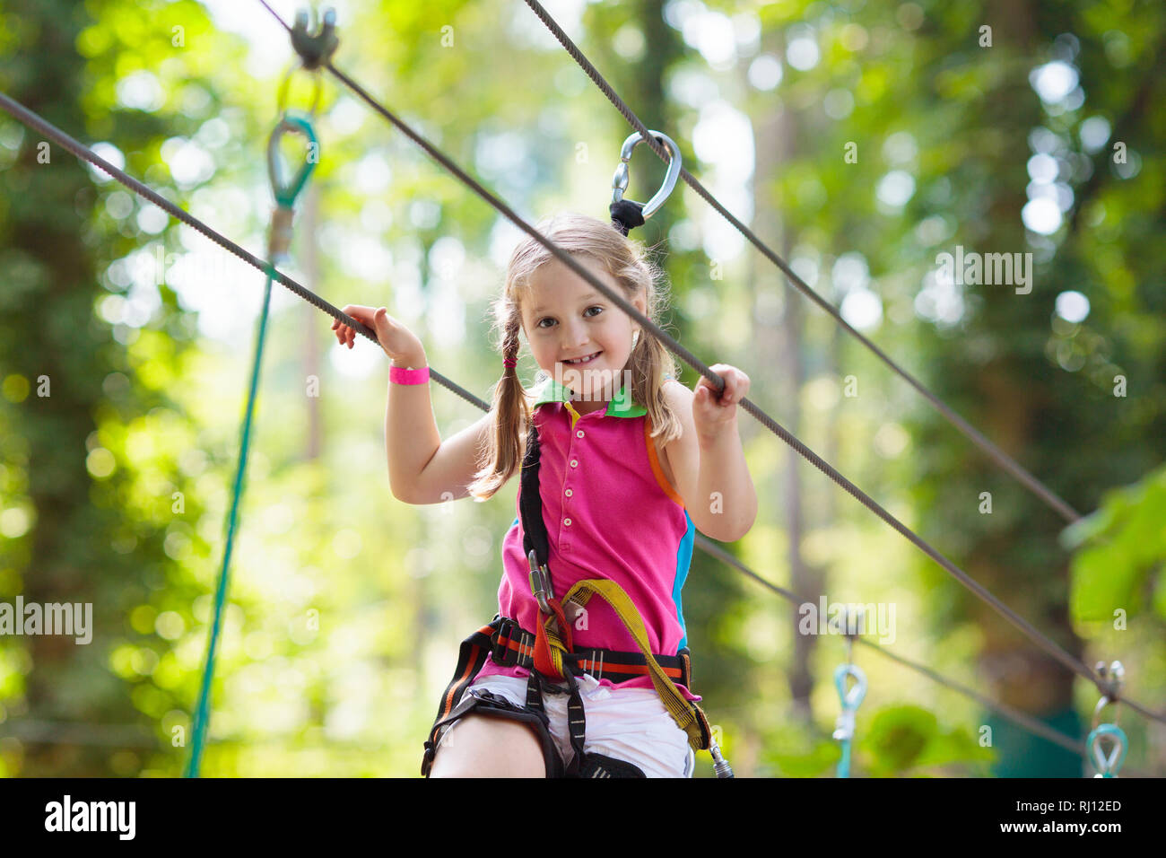 Child in forest adventure park. Kids climb on high rope trail. Agility ...