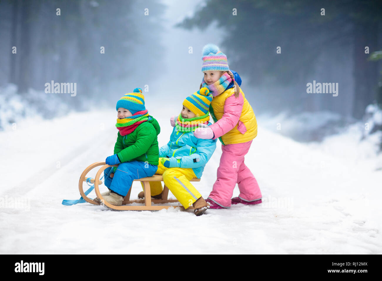 Little girl and boy enjoying sleigh ride. Child sledding. Toddler kid ...