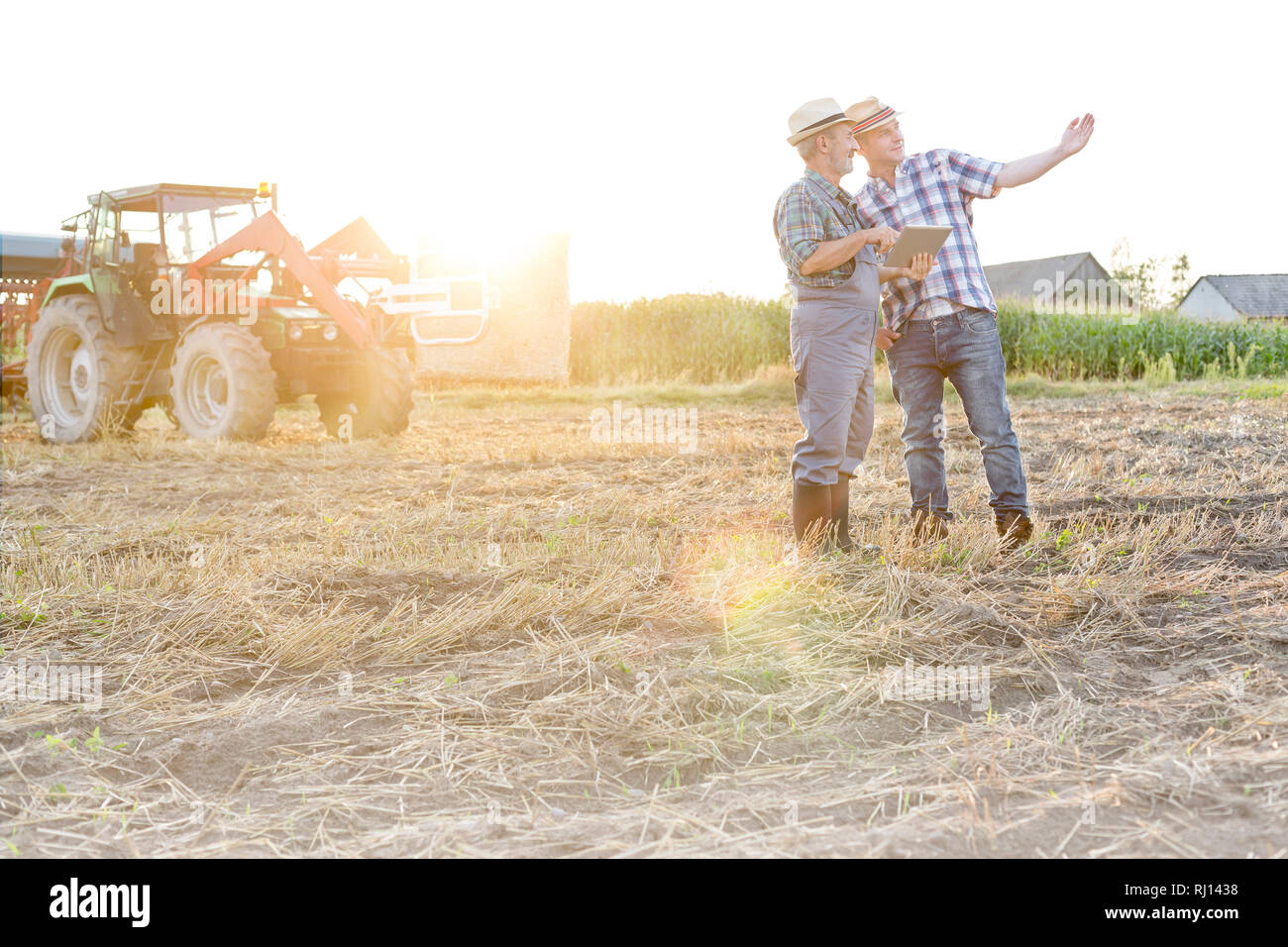 Farmers talking while using digital tablet at farm on sunny day Stock ...