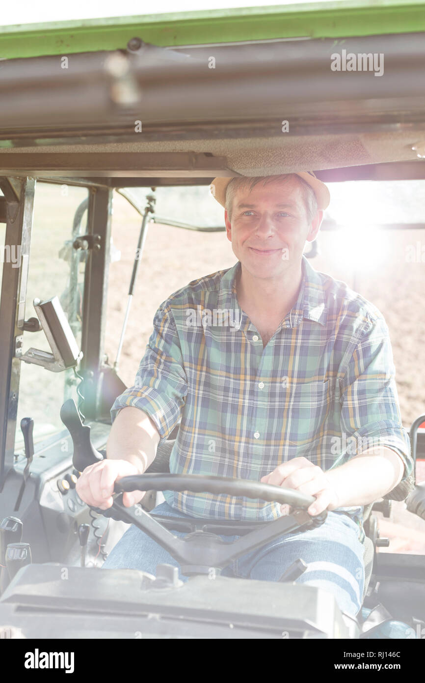 Smiling confident mature farmer driving tractor at farm Stock Photo - Alamy