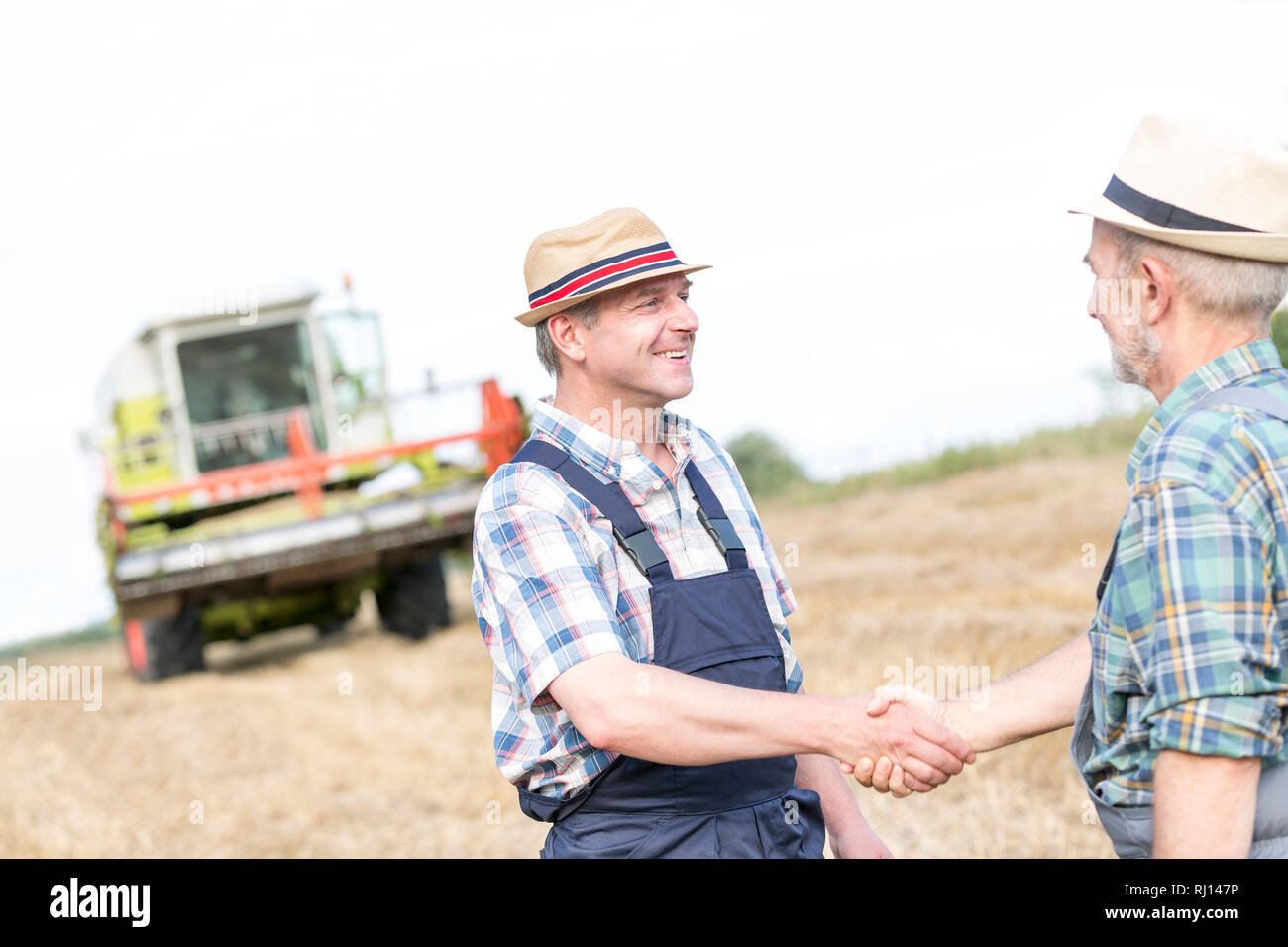 Farmers shaking hands while standing on field at farm Stock Photo - Alamy