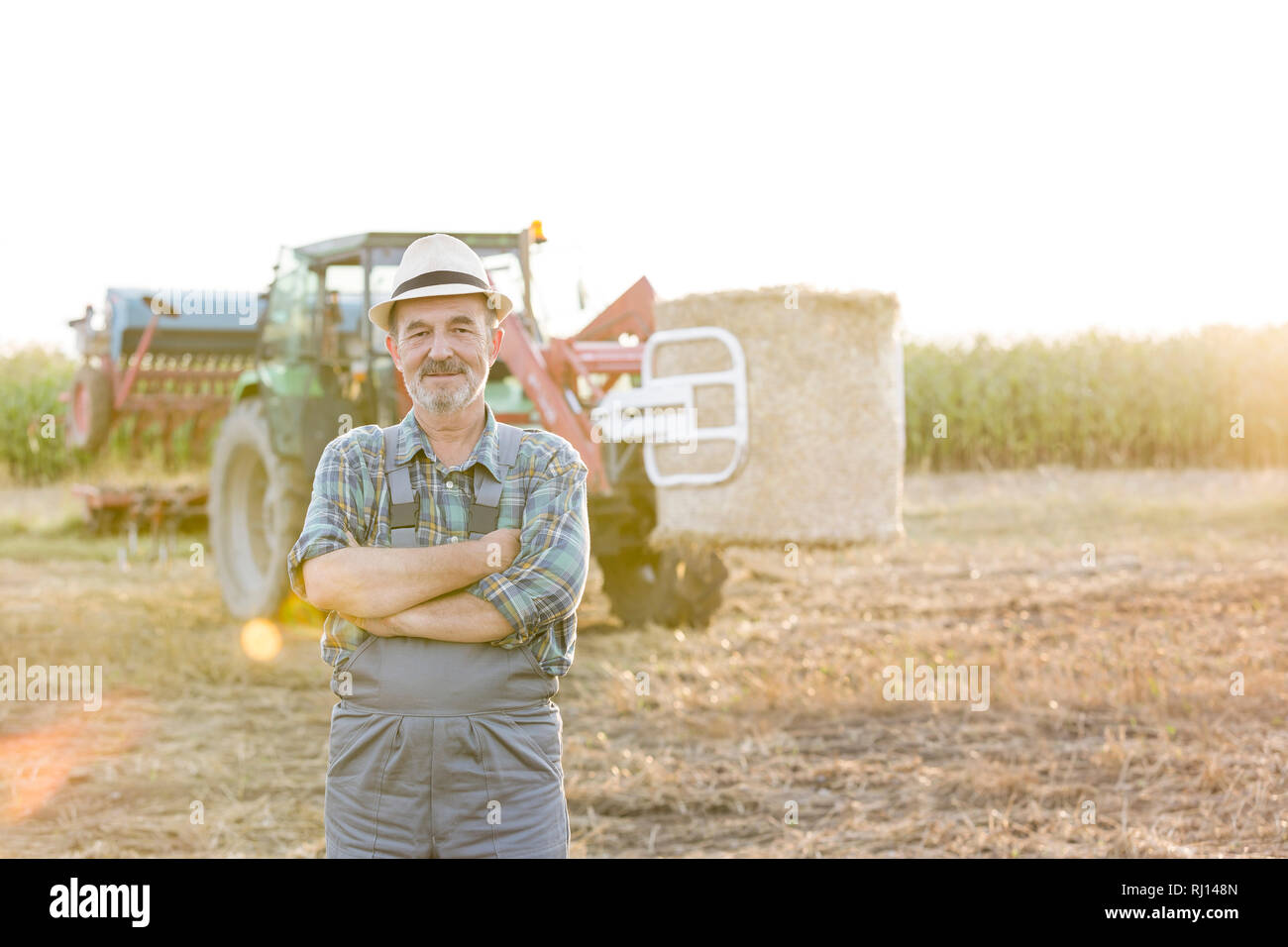 Portrait of farmer standing with arms crossed on field against ...