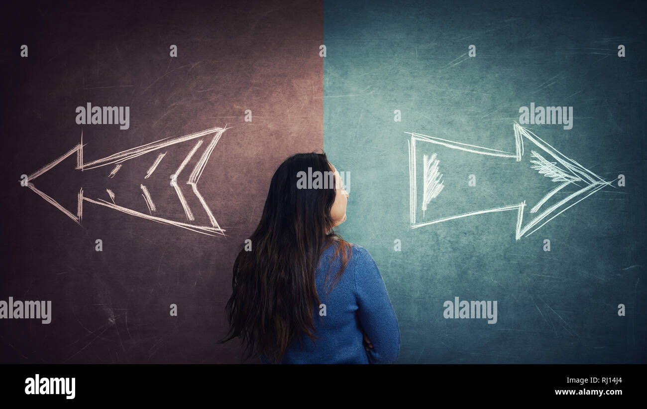 Puzzled woman rear view and split blackboard with arrows going in two ...