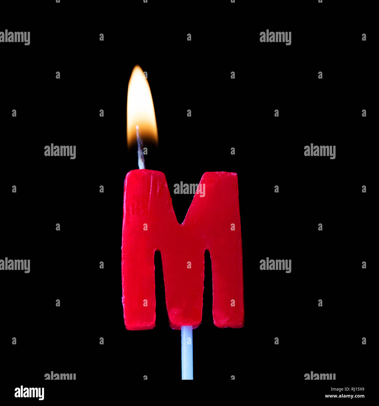 Letter M celebration birthday candle against a black background Stock ...