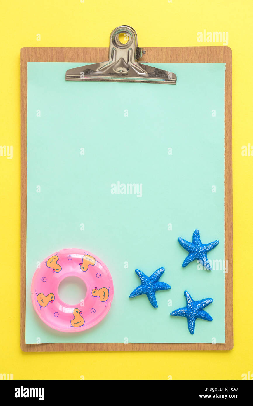 Flat lay of blank paper clipboard with sea stars and inflatable pool ...