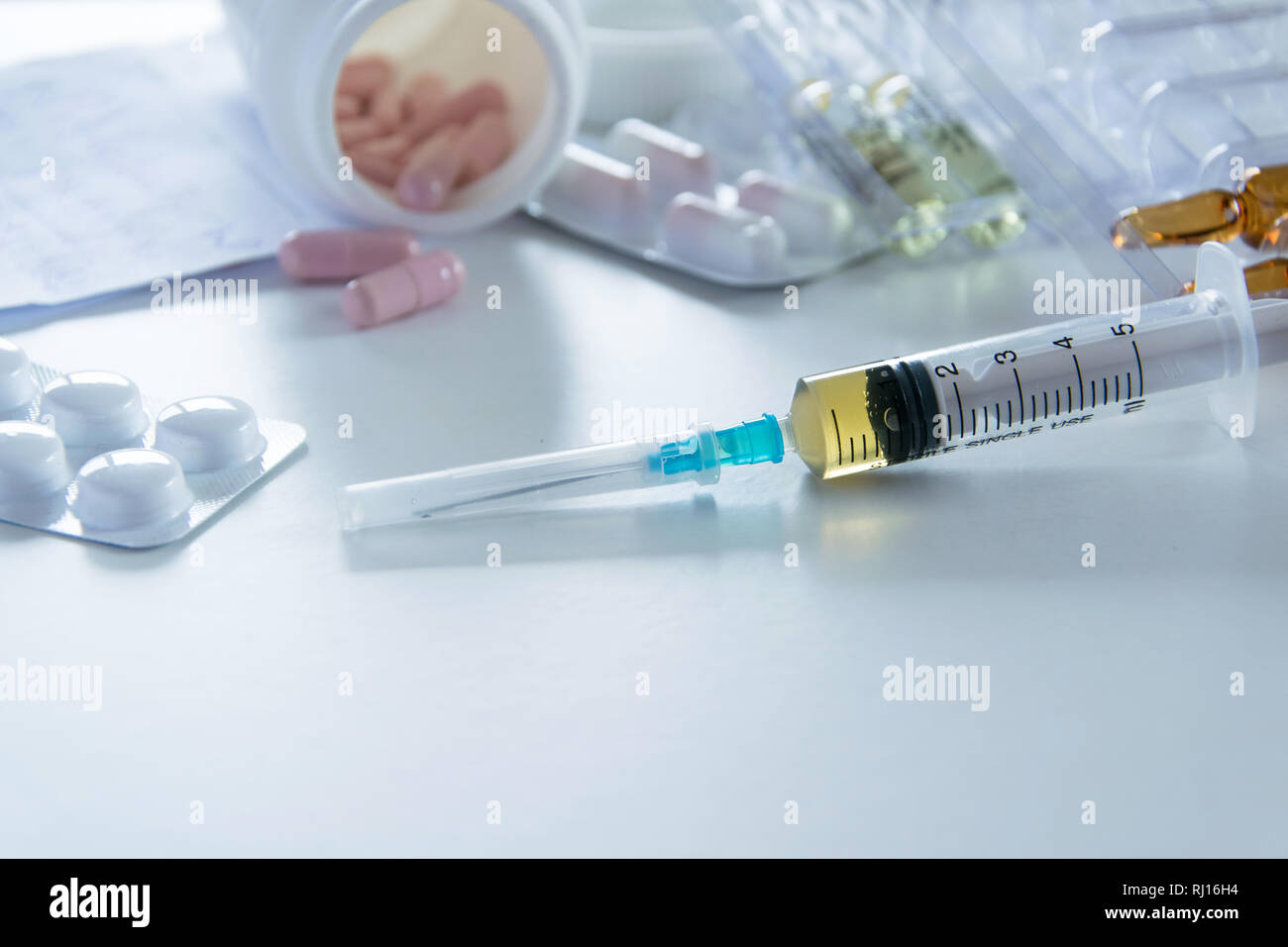 Medical syringe with injection solution, medicine pills and capsules on ...