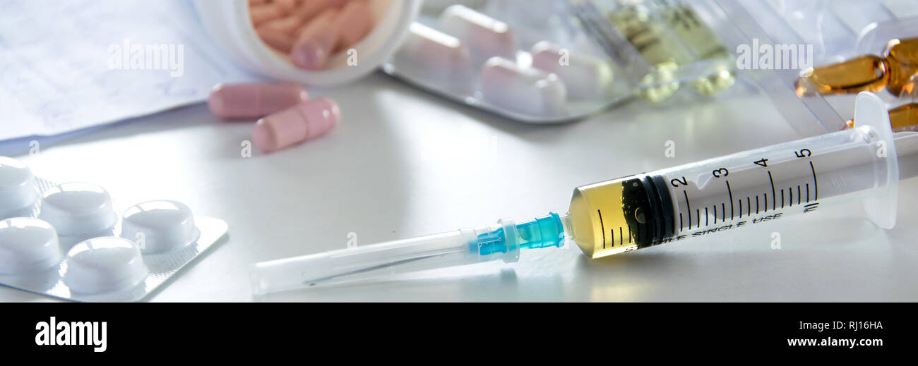Medical syringe with injection solution, medicine pills and capsules on ...
