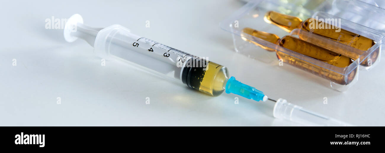 Medical syringe with injection solution, medicine pills and capsules on ...