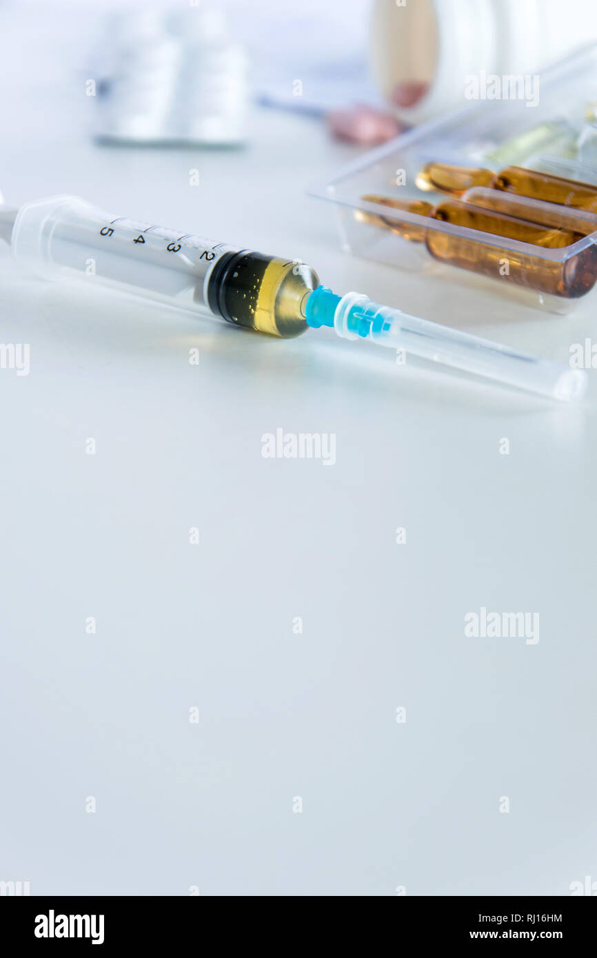 Medical syringe with injection solution, medicine pills and capsules on ...